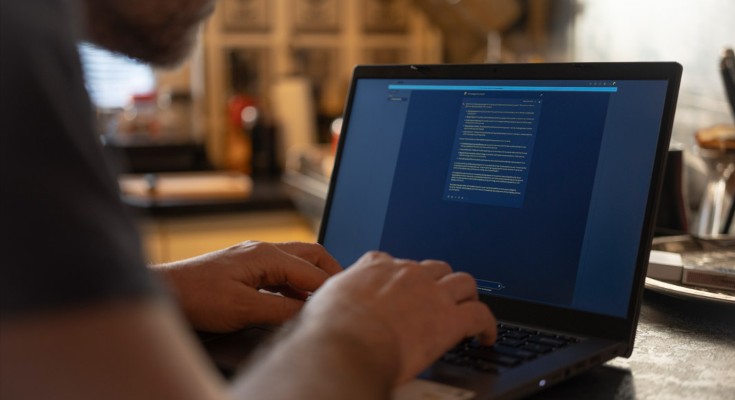 A person sat at a laptop, working on a text file